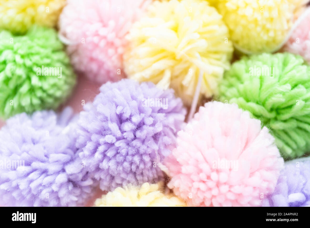 Pastel color pom poms on a pink background Stock Photo - Alamy