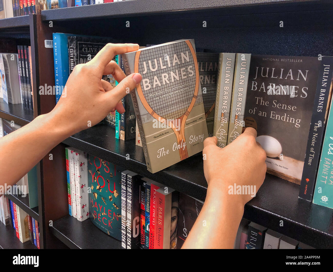 Man looking through books at a library or a book store. Hands holding a ...