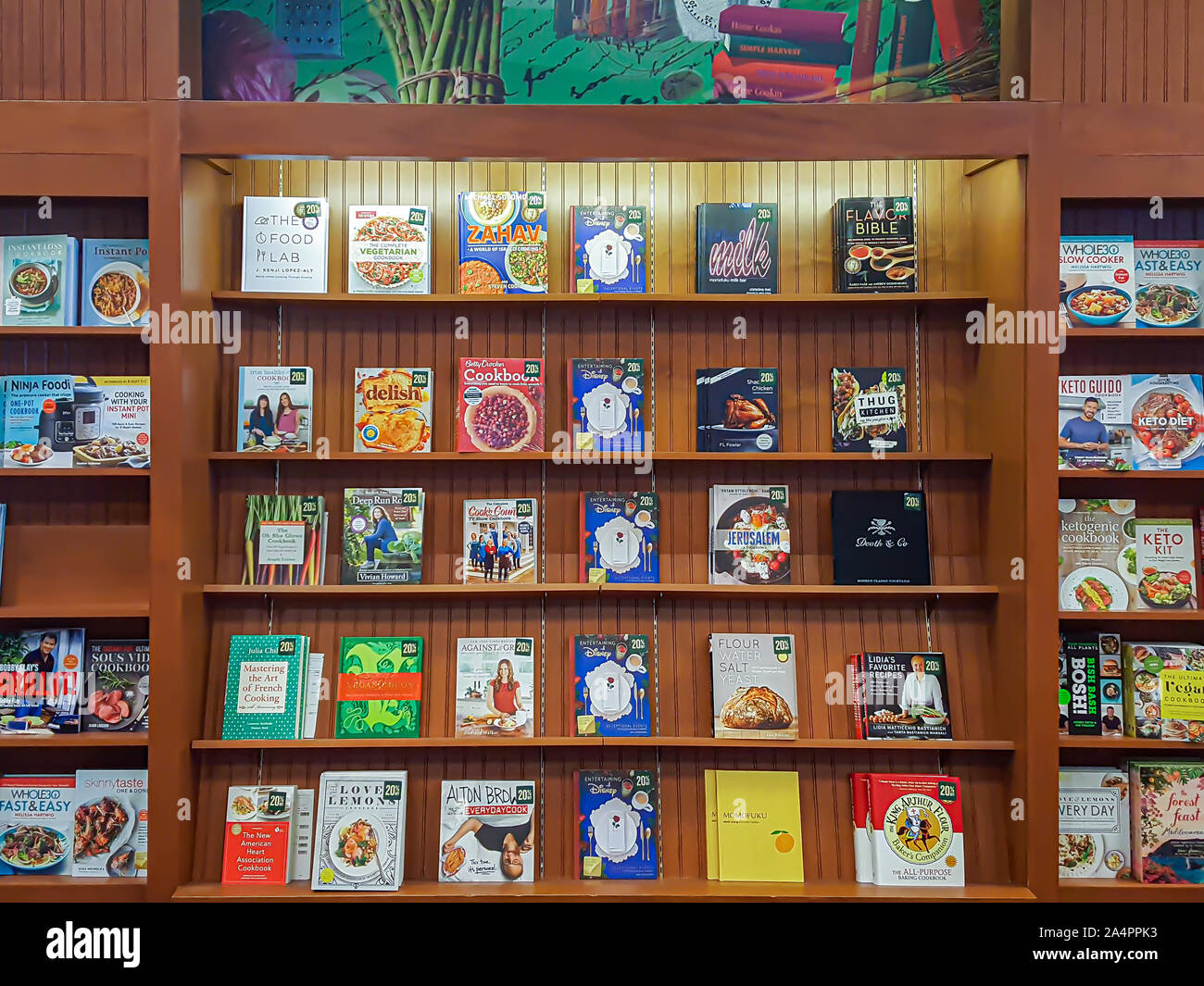 Rows of different colorful books lying on the shelves in the modern ...