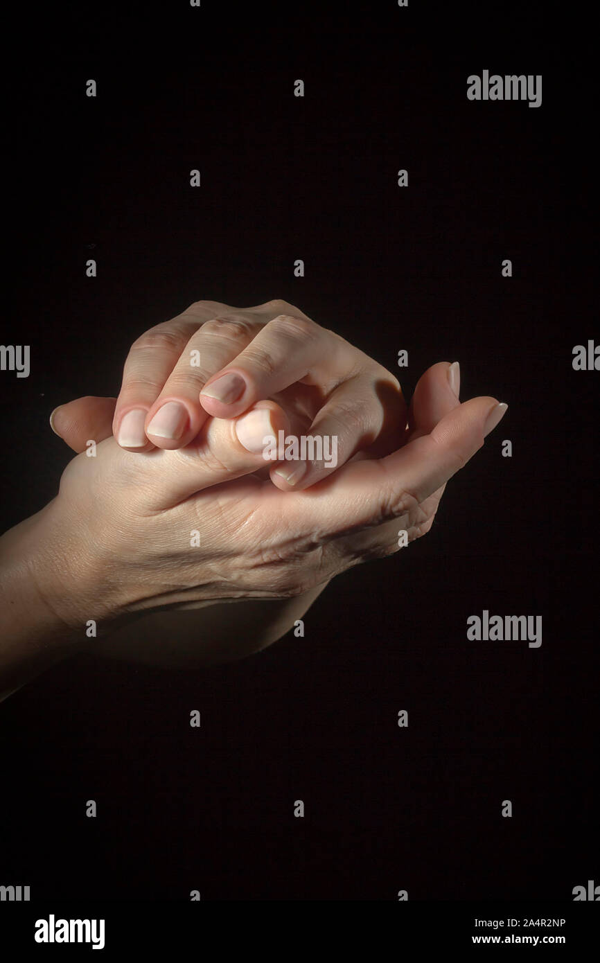 Female folded hands on a black background Stock Photo - Alamy