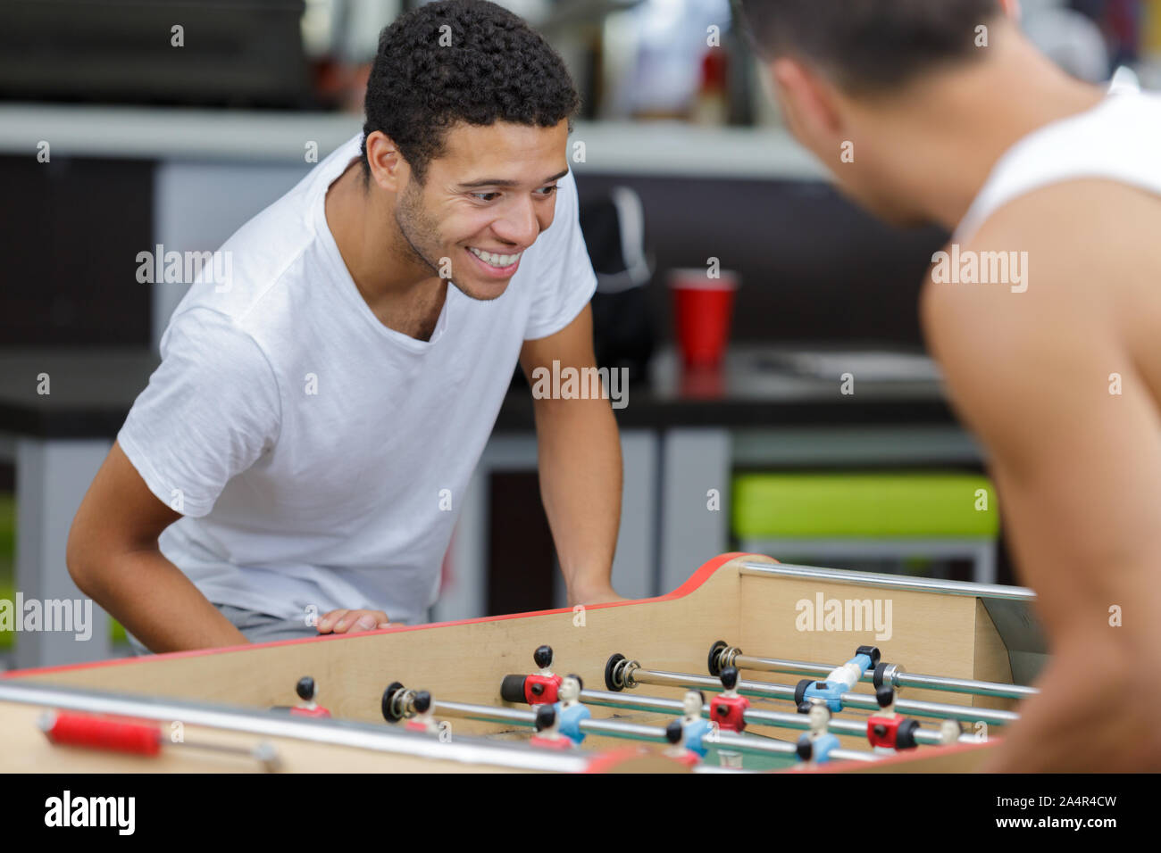 happy men playing football table Stock Photo - Alamy