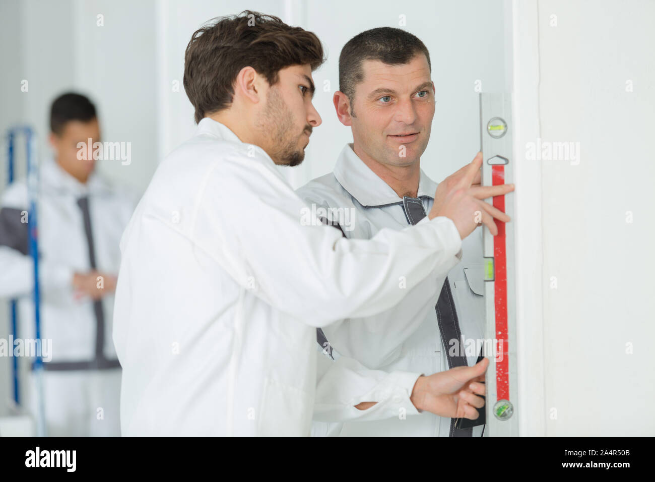 apprentice builder with foreman using spirit level Stock Photo - Alamy