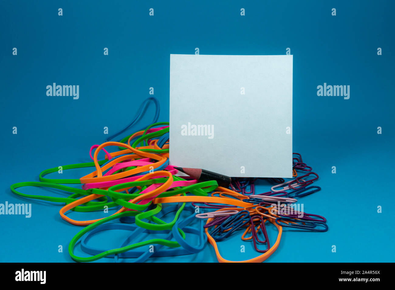 Pile of colorful rubber bands over blue background with a white sheet ...