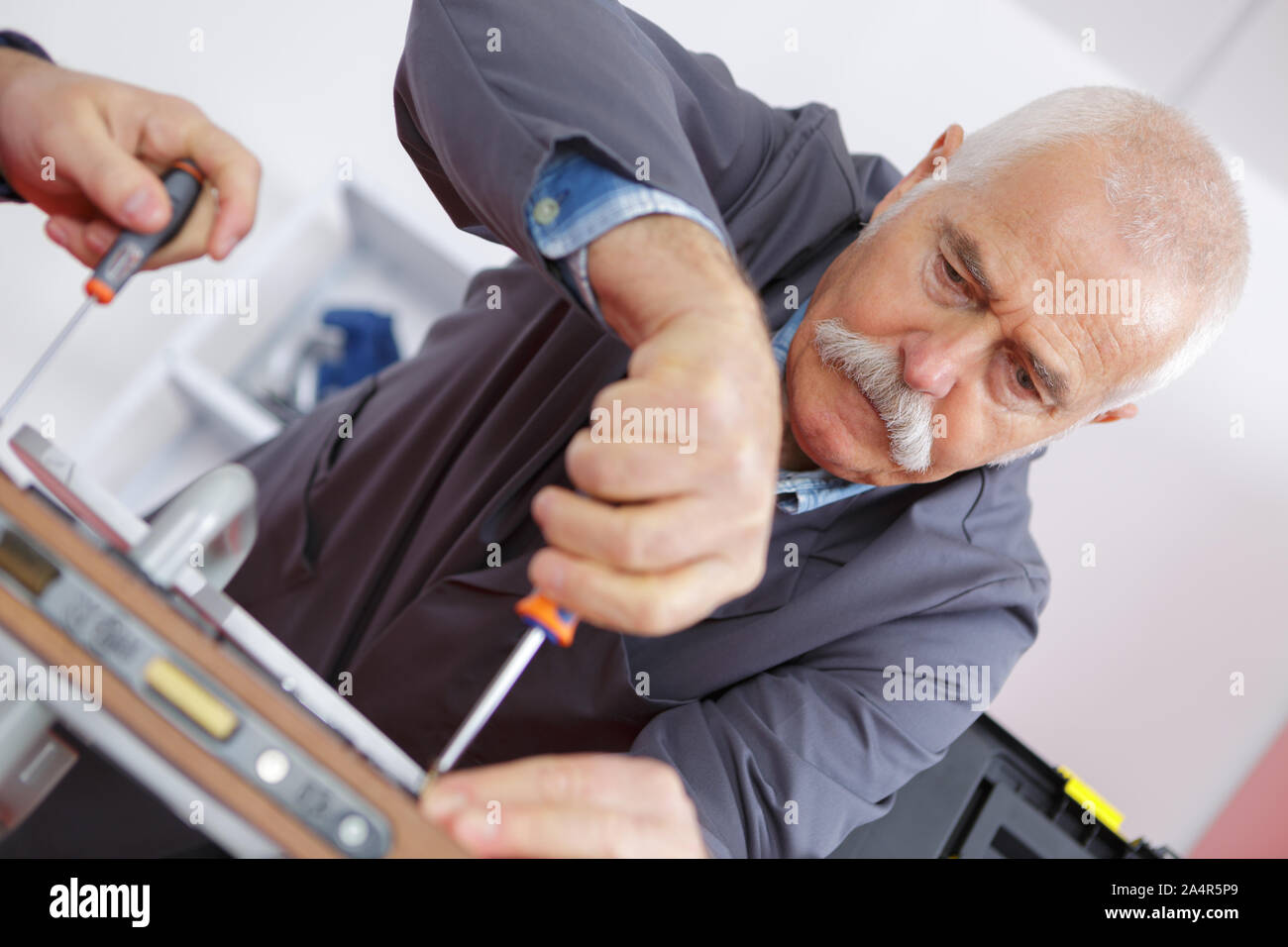 senior man repairing gate lock with screwdriver Stock Photo - Alamy