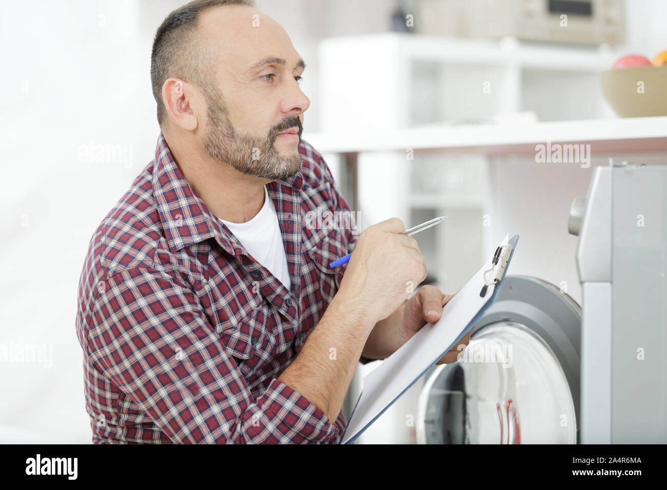repairman examining a washing machine Stock Photo - Alamy