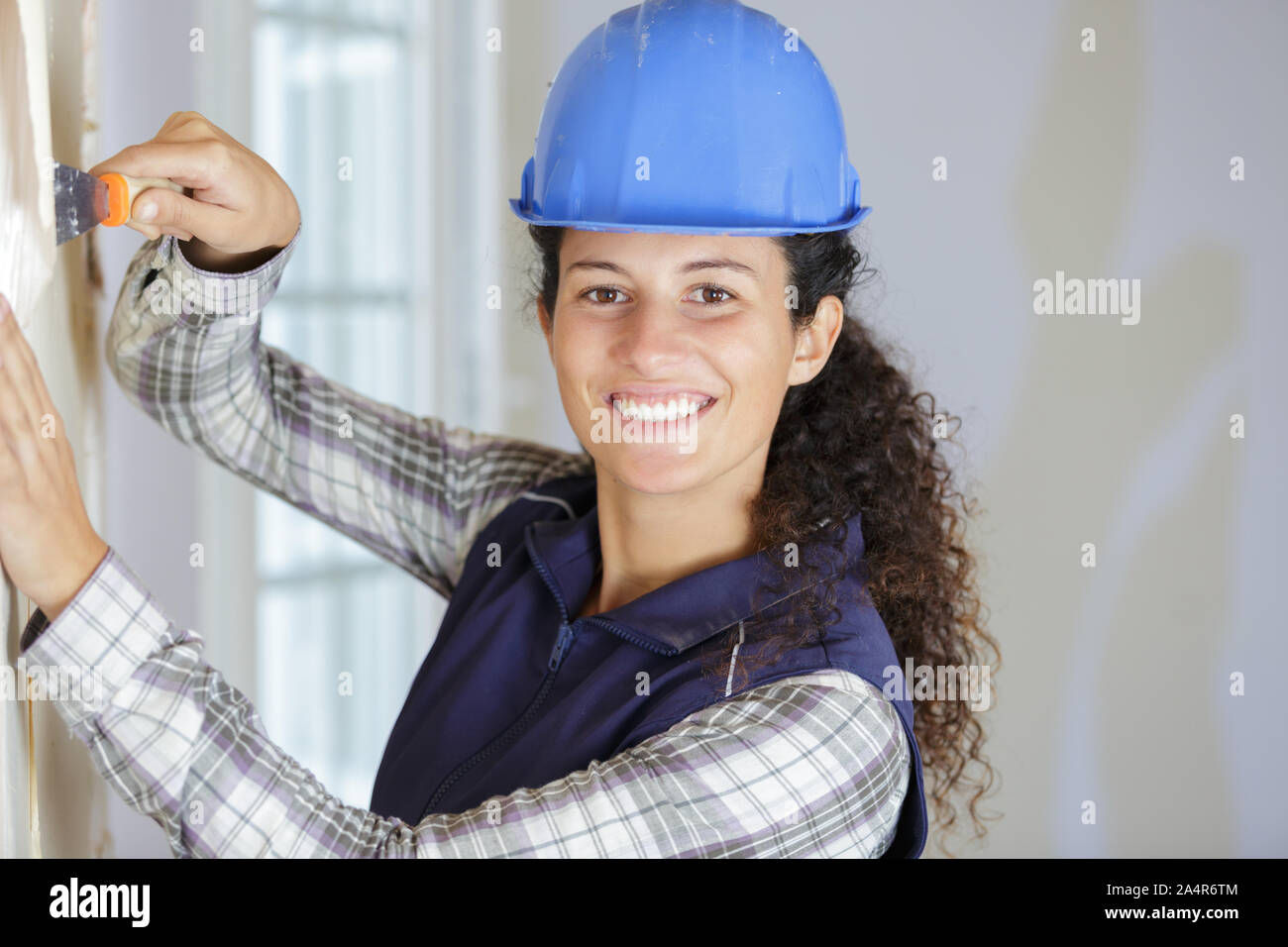 female builder using wallpaper scraper Stock Photo - Alamy