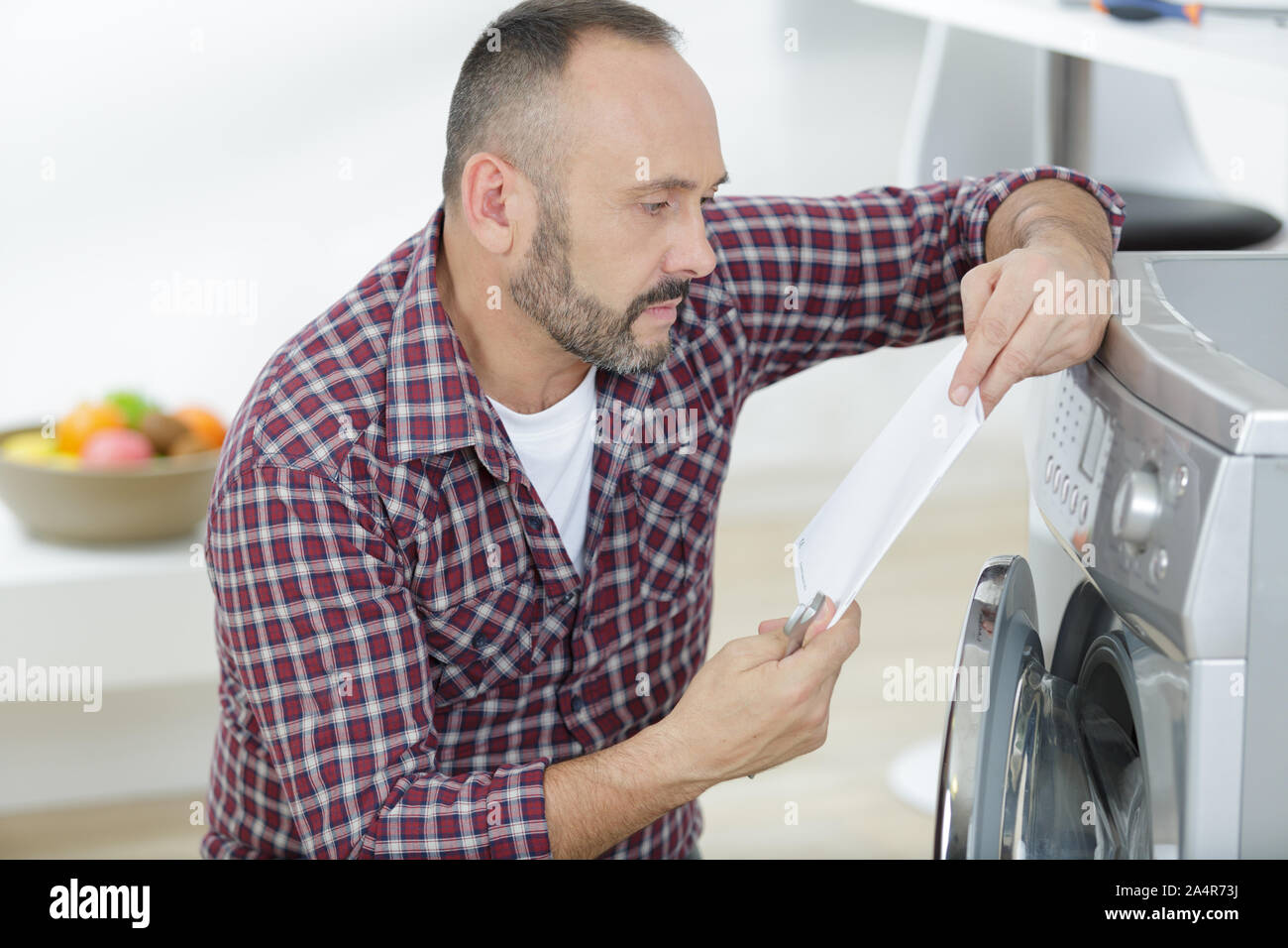 man reading washing machine instructions Stock Photo - Alamy