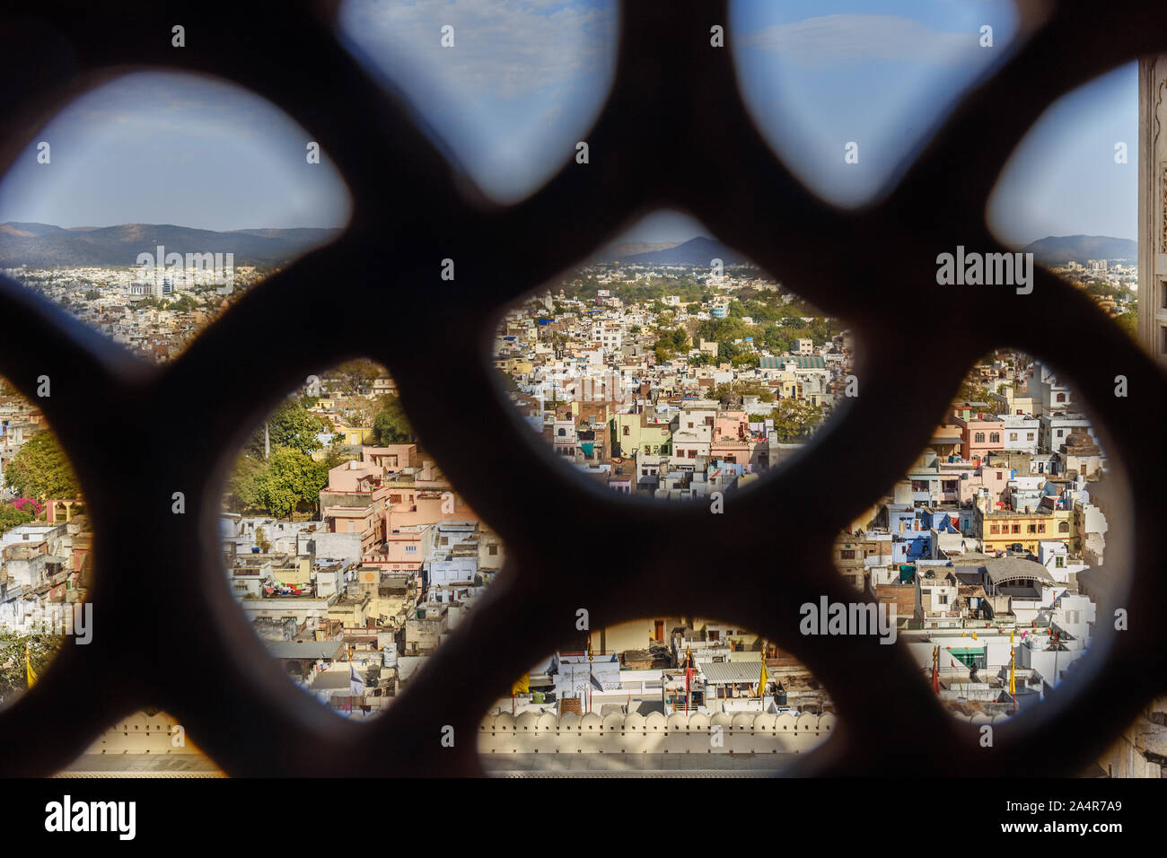 View of city through carving window of City palace in Udaipur ...