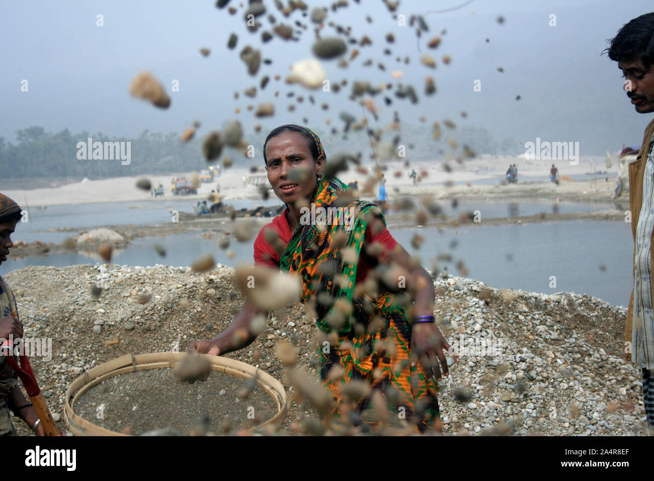 A female "stone labourer" strains rocks and peblles from sand, on a ...