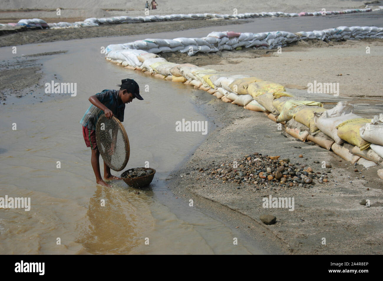 A young boy at work on the banks of the Dauki river. The river in its ...