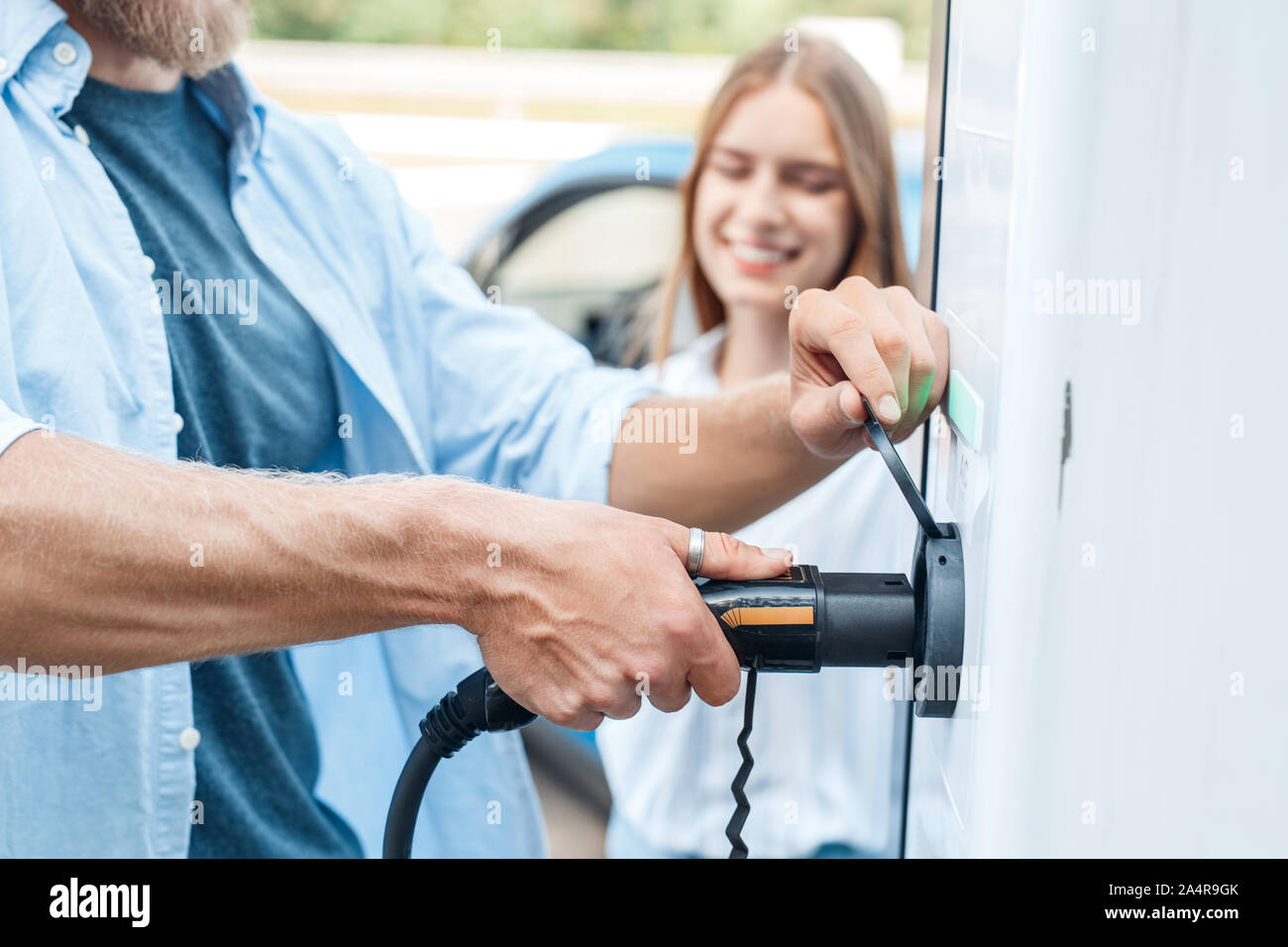 Man holding power cable supply plugged in public charging station Stock ...