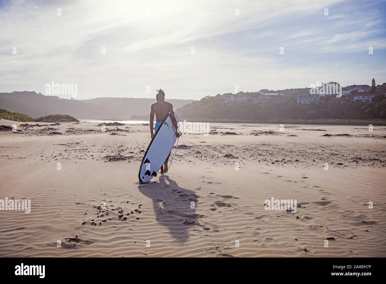 A young man walking with his surfboard on Chintsa Beach Stock Photo - Alamy