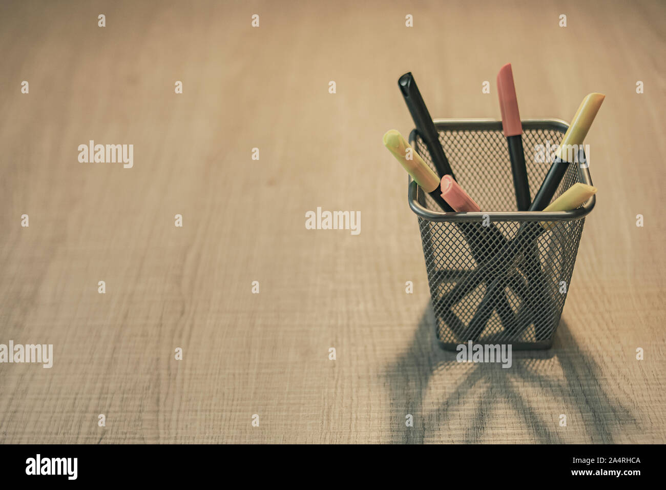 Metallic net bin with office red, yellow and black pens Stock Photo - Alamy