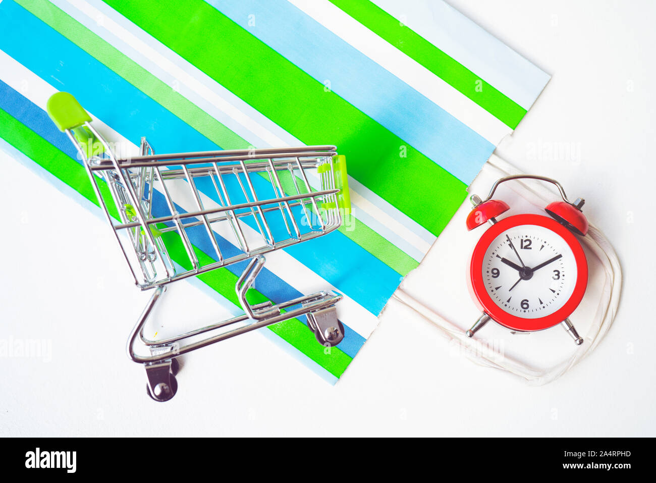 Red clock, shopping cart and paper bag on isolated white backgroun ...