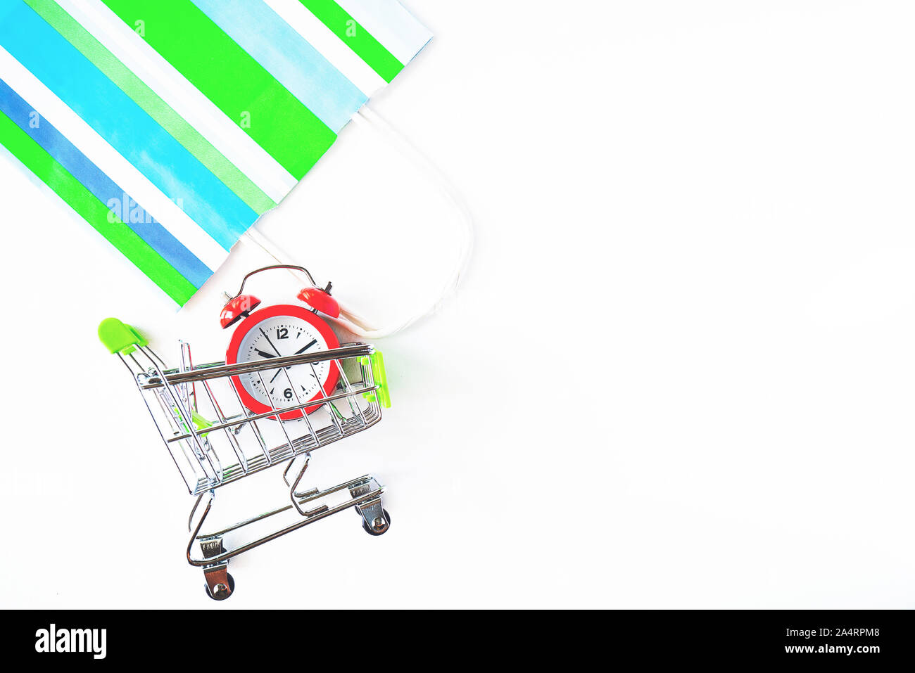 Red clock, shopping cart and paper bag on isolated white backgroun ...