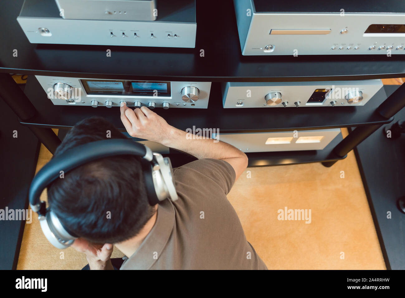 Man turning up the volume on home Hi-Fi stereo Stock Photo - Alamy