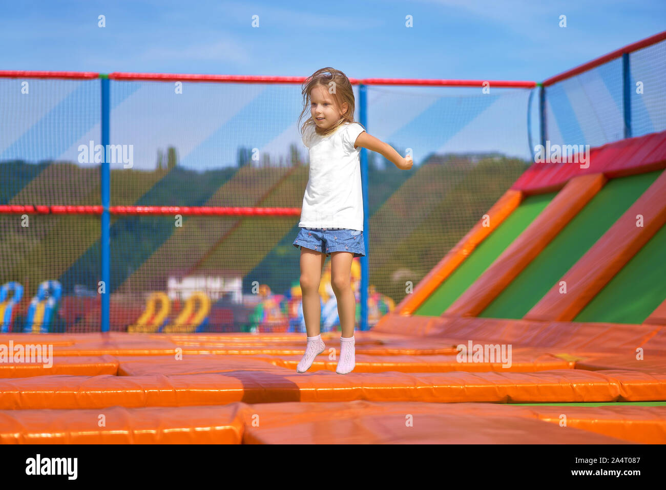 Little pretty girl having fun outdoor. Jumping on trampoline in ...