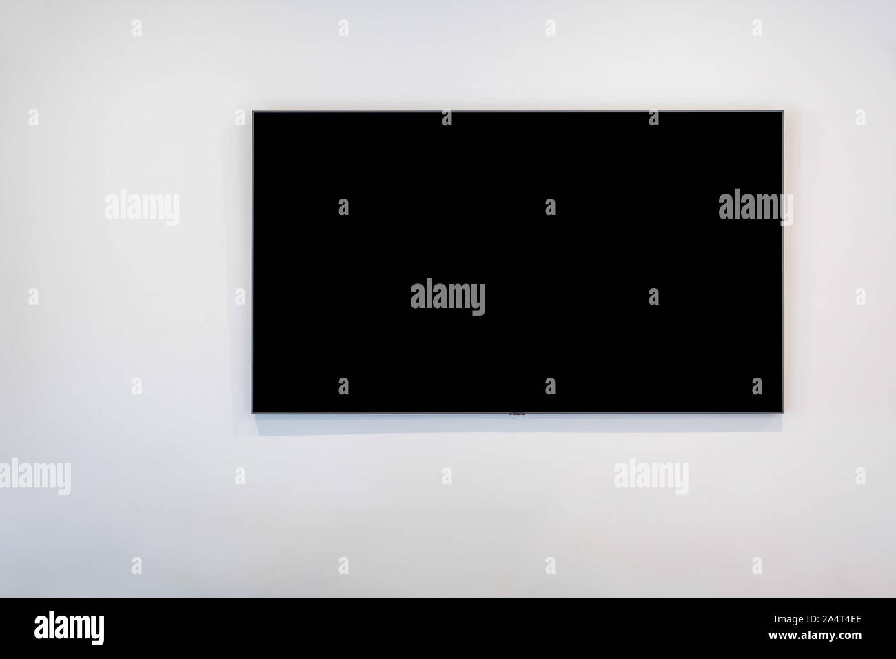 Black flat screen TV on white wall with copy space Stock Photo - Alamy