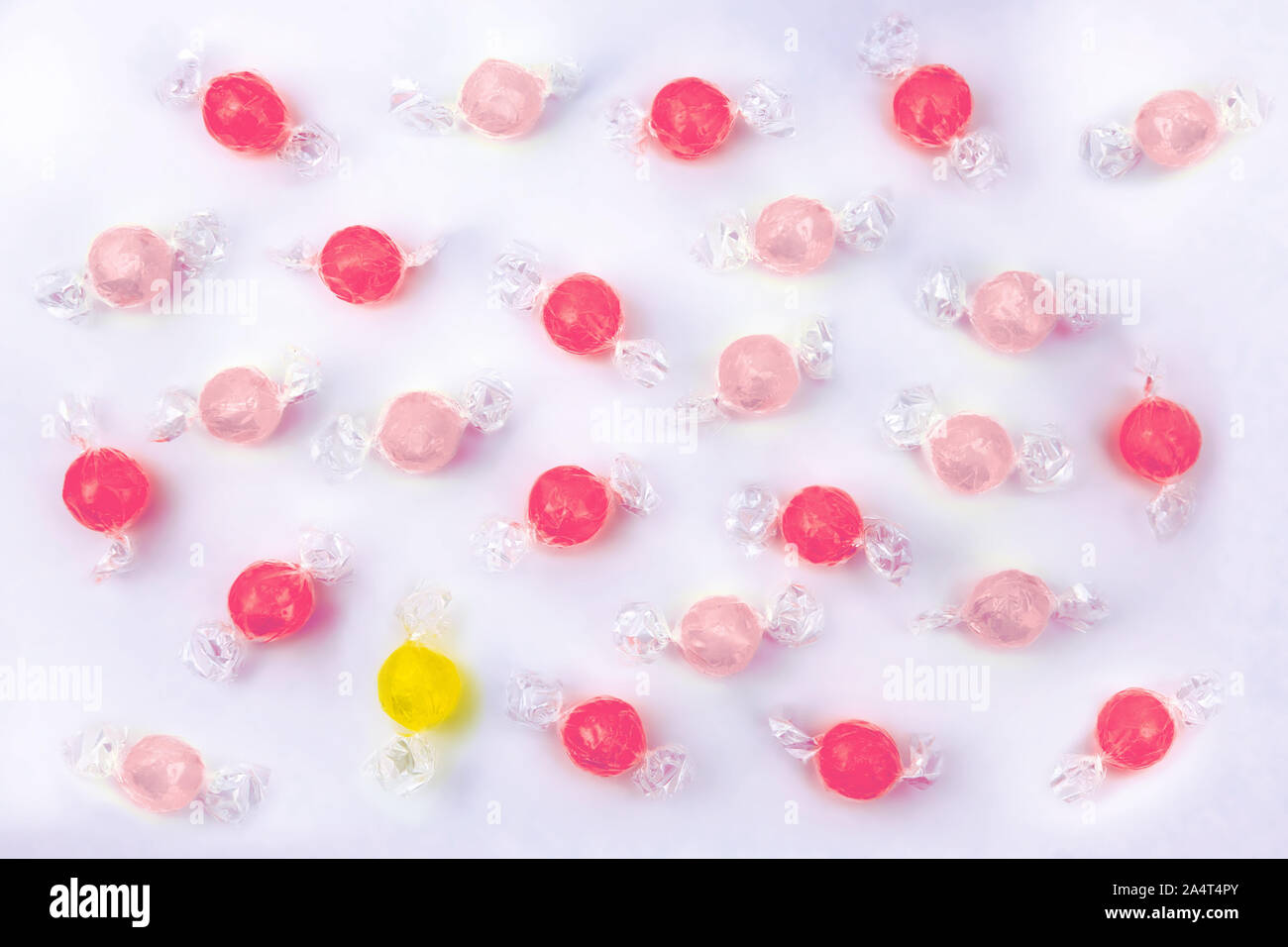 A yellow candy among many pink candies. Concept about differences ...