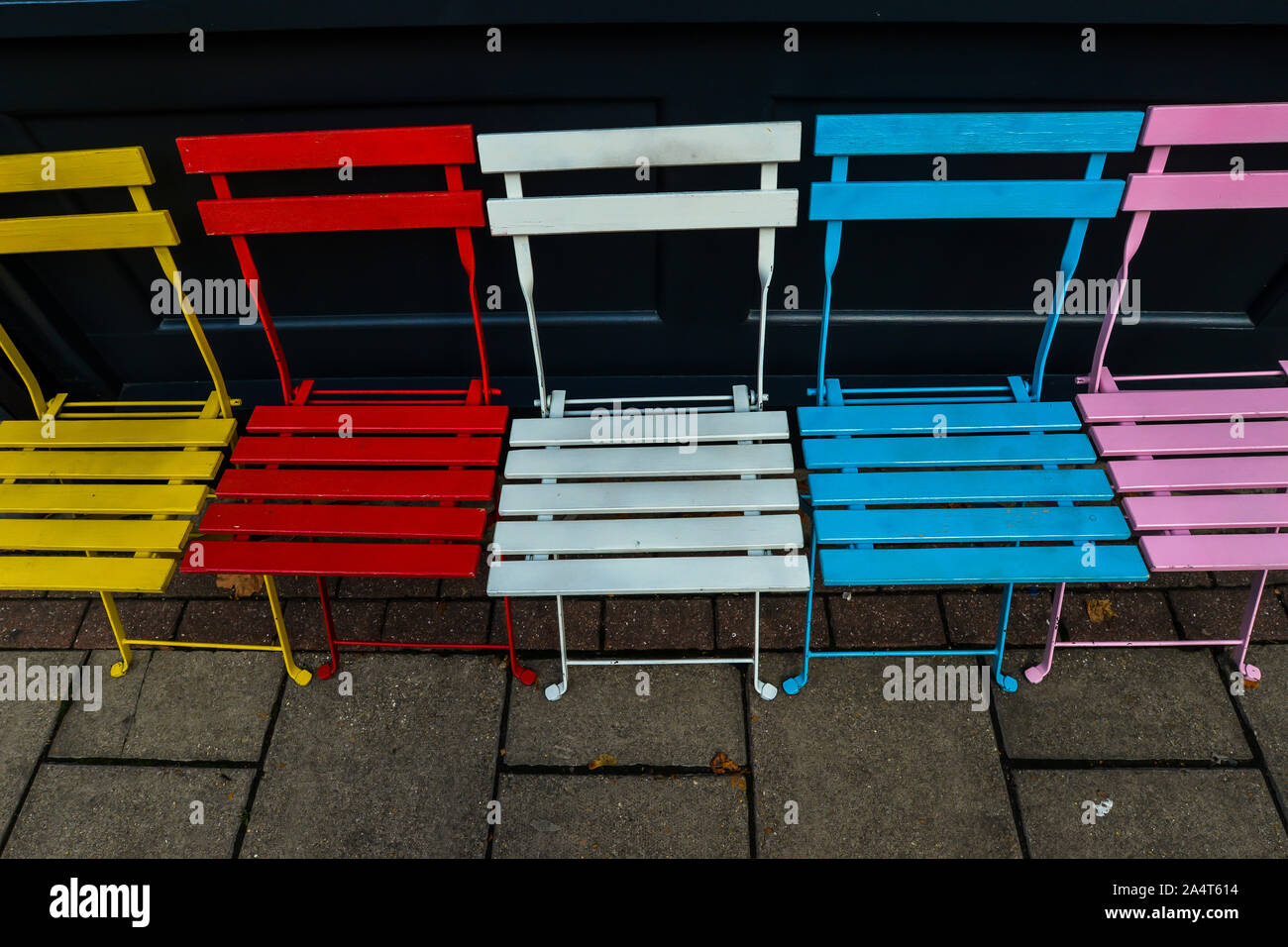 Colorful chairs lined up in the street Stock Photo - Alamy