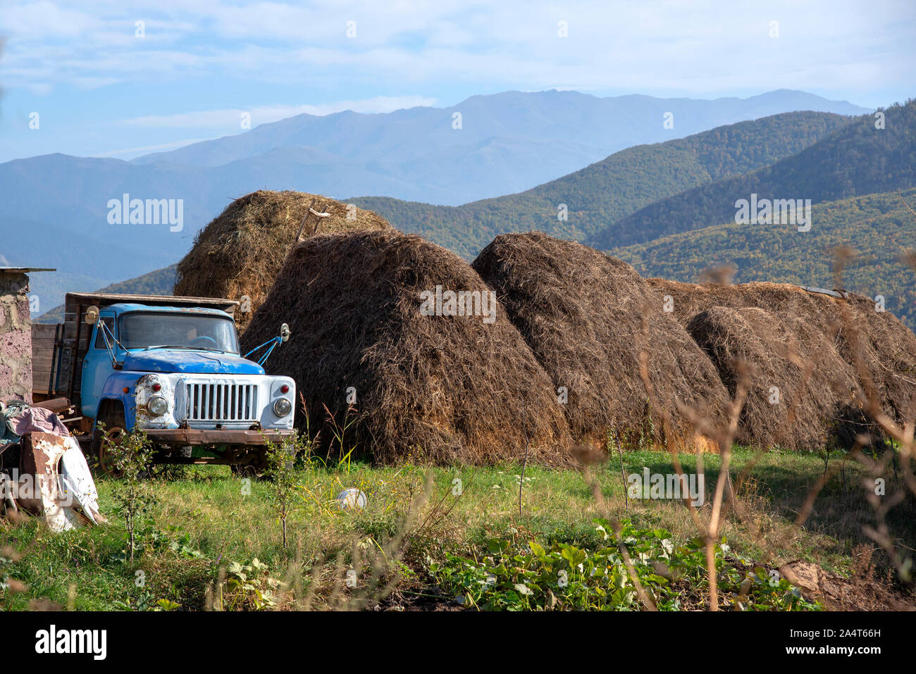 The huge haystacks and a truck on a background of mountains and sky ...