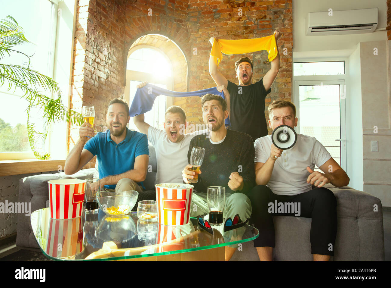 Group of friends watching game on TV at home. Sport fans spending time ...