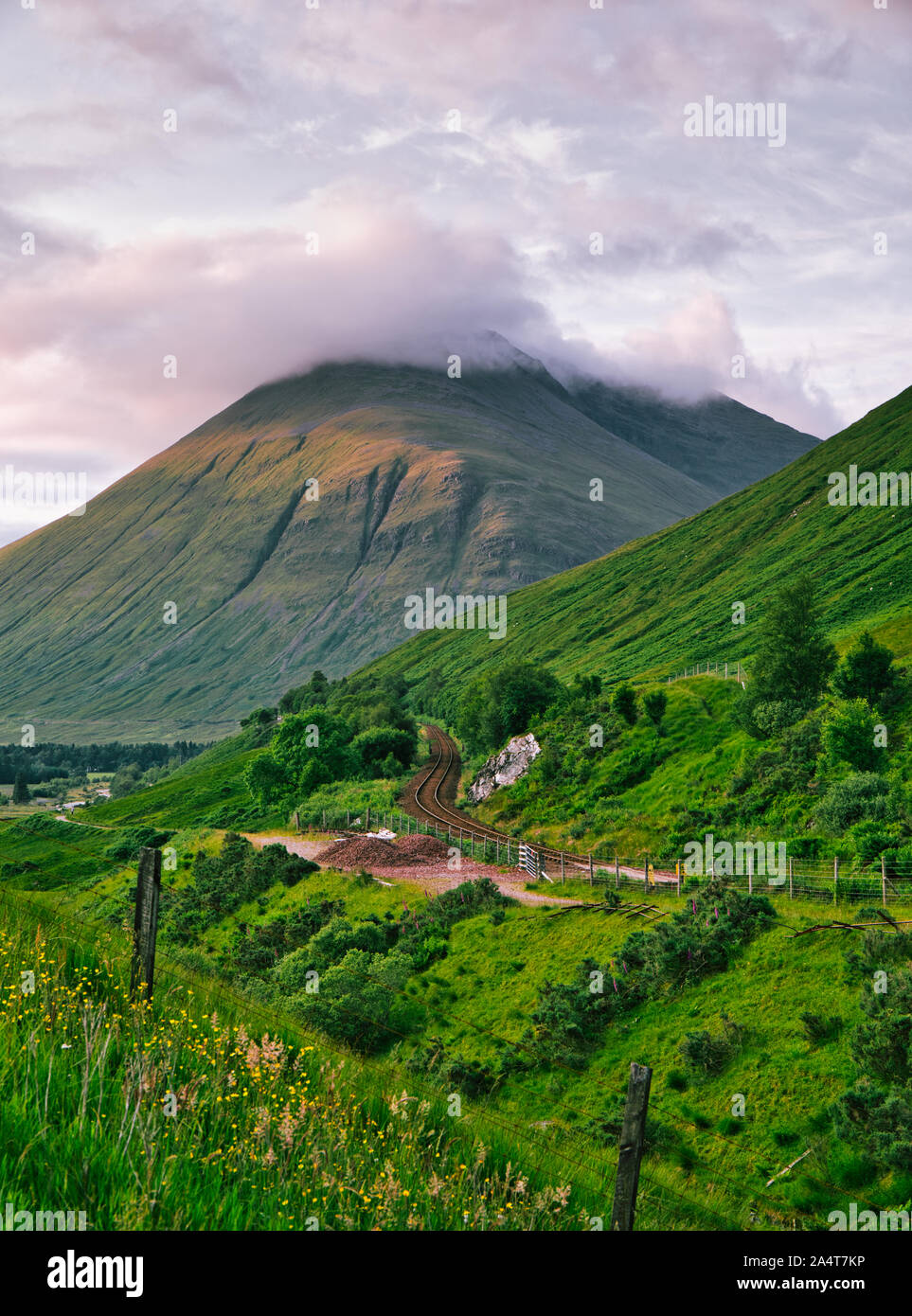 Railway line winding through the majestic Scottish Highlands at dusk ...