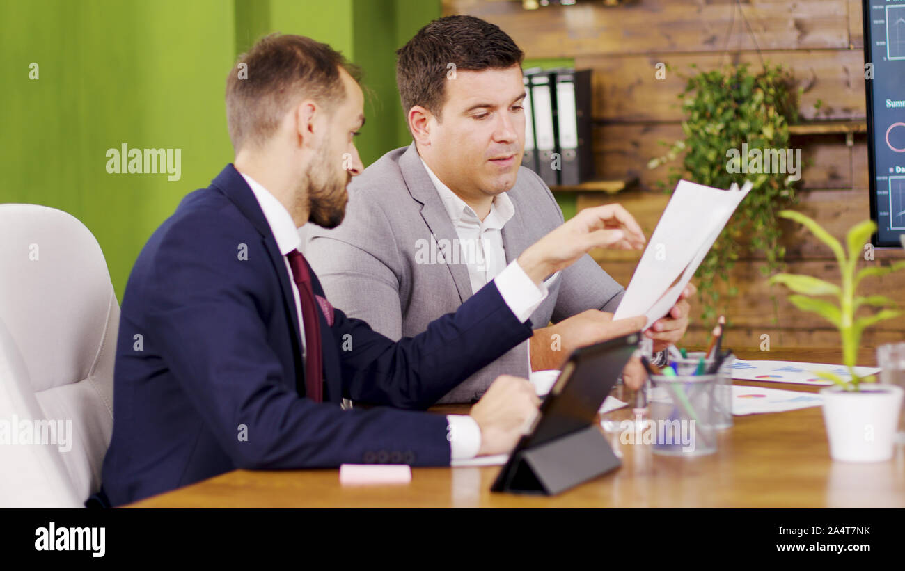 Two colleagues in business suits in the conference room looking at ...