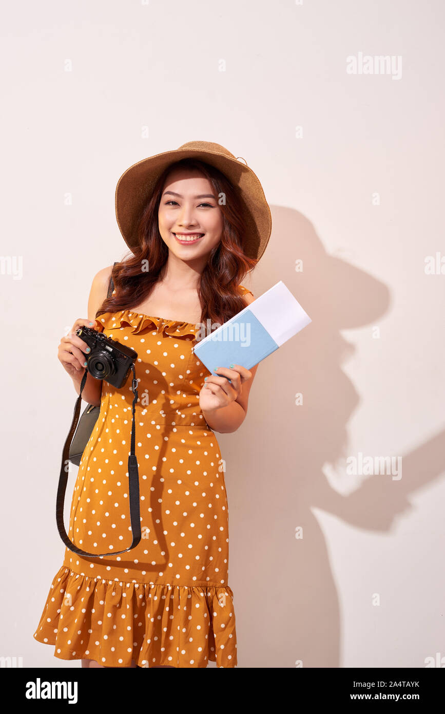 Portrait Of A Happy Young Woman In Hat Holding Camera And Showing Passport While Standing