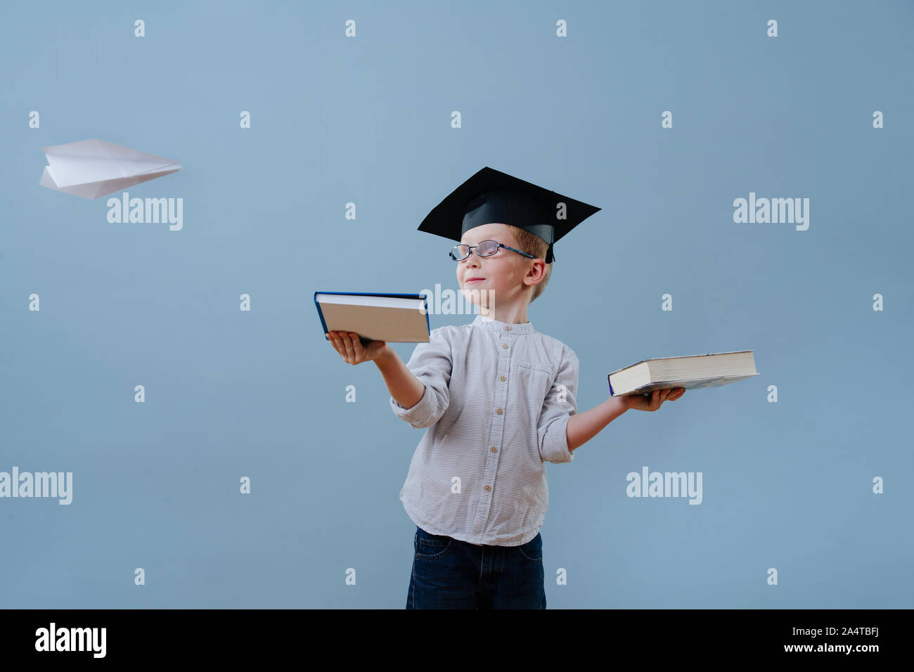 Redhead first grader boy in glasses and student hat looks at paper ...