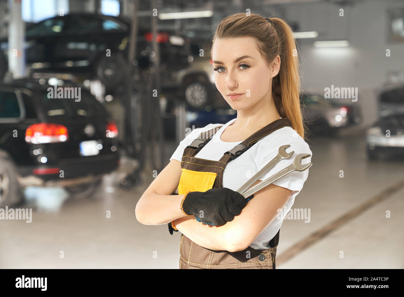 Charming, beautiful girl holding wrenches, looking at camera, posing ...