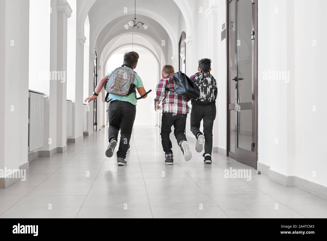 Group of schoolboys with school backpacks running in hallway of school ...