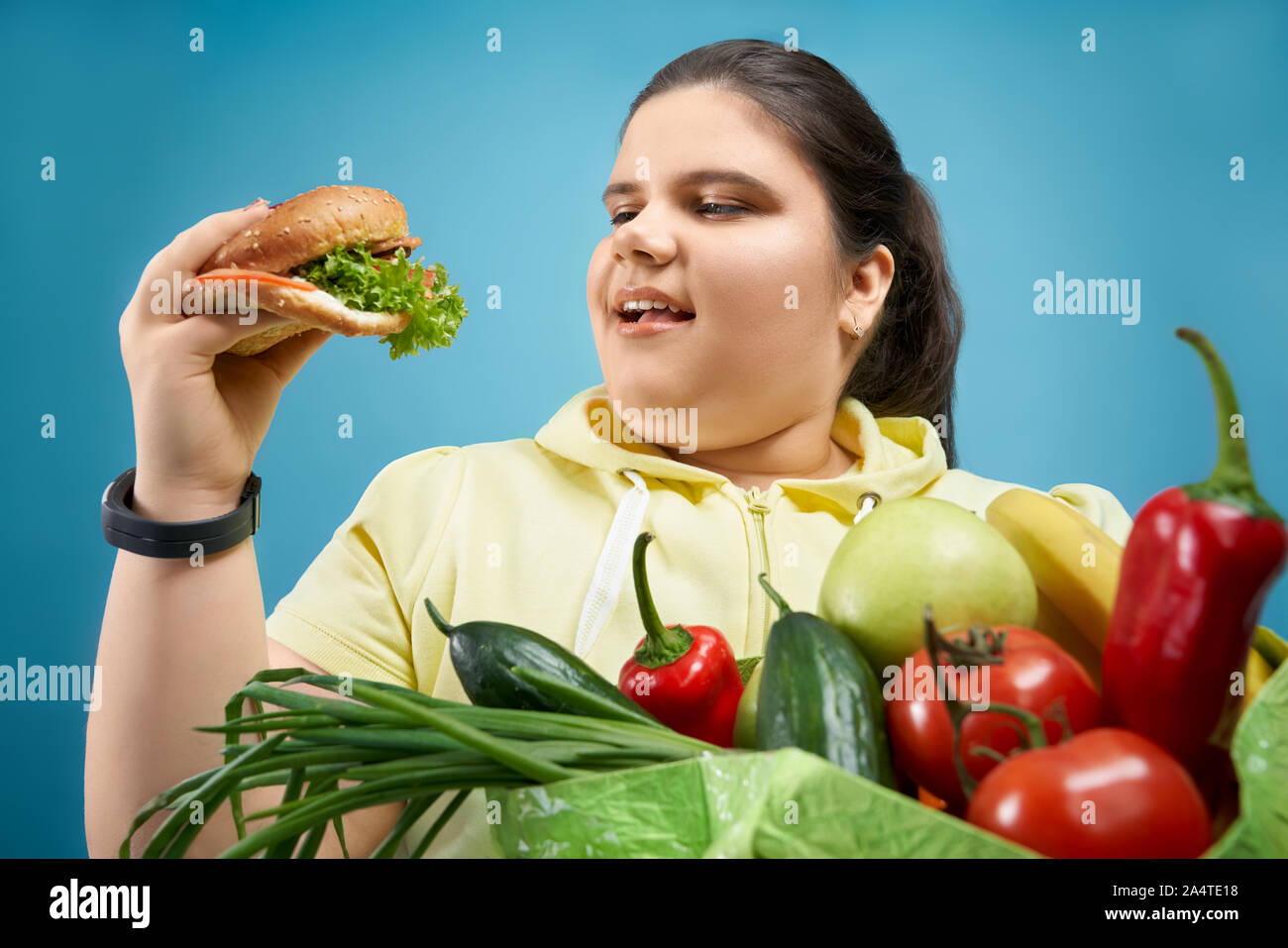 Portrait of overweight girl that is pretending to eat burger but not ...
