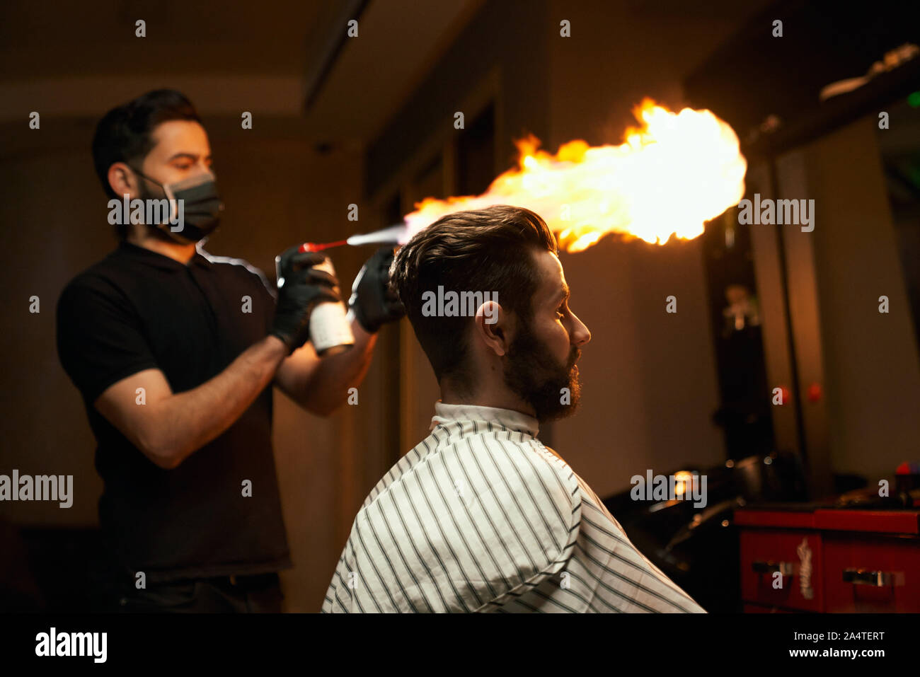 Professional handsome barber with black mask on mouth is going to make ...