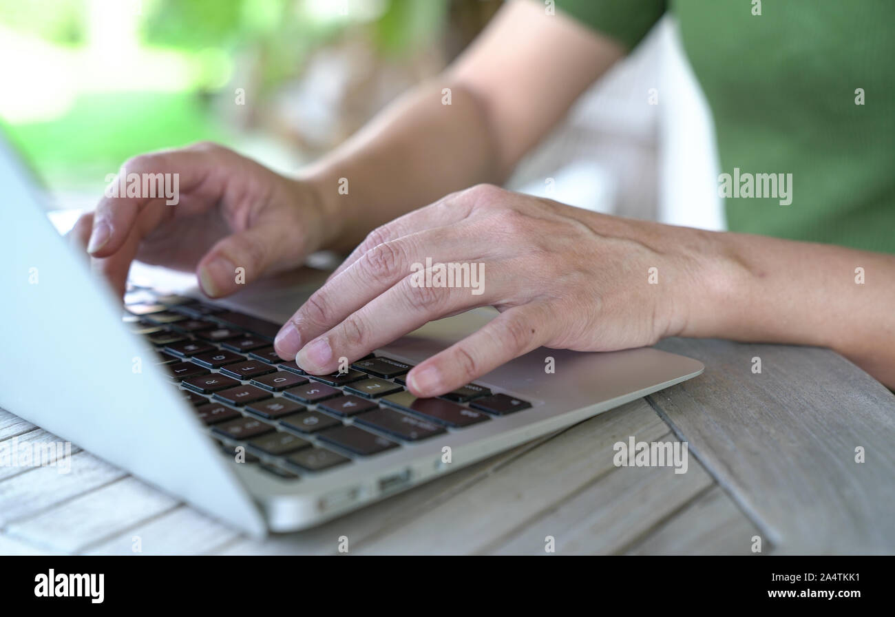 Woman's hands busy typing on keyboard of a laptop. Home or garden ...