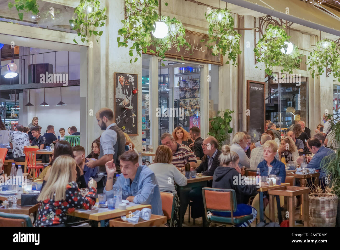 Hellenic nightlife scene of people at outdoors tavern restaurants. Unidentified crowd eating ...