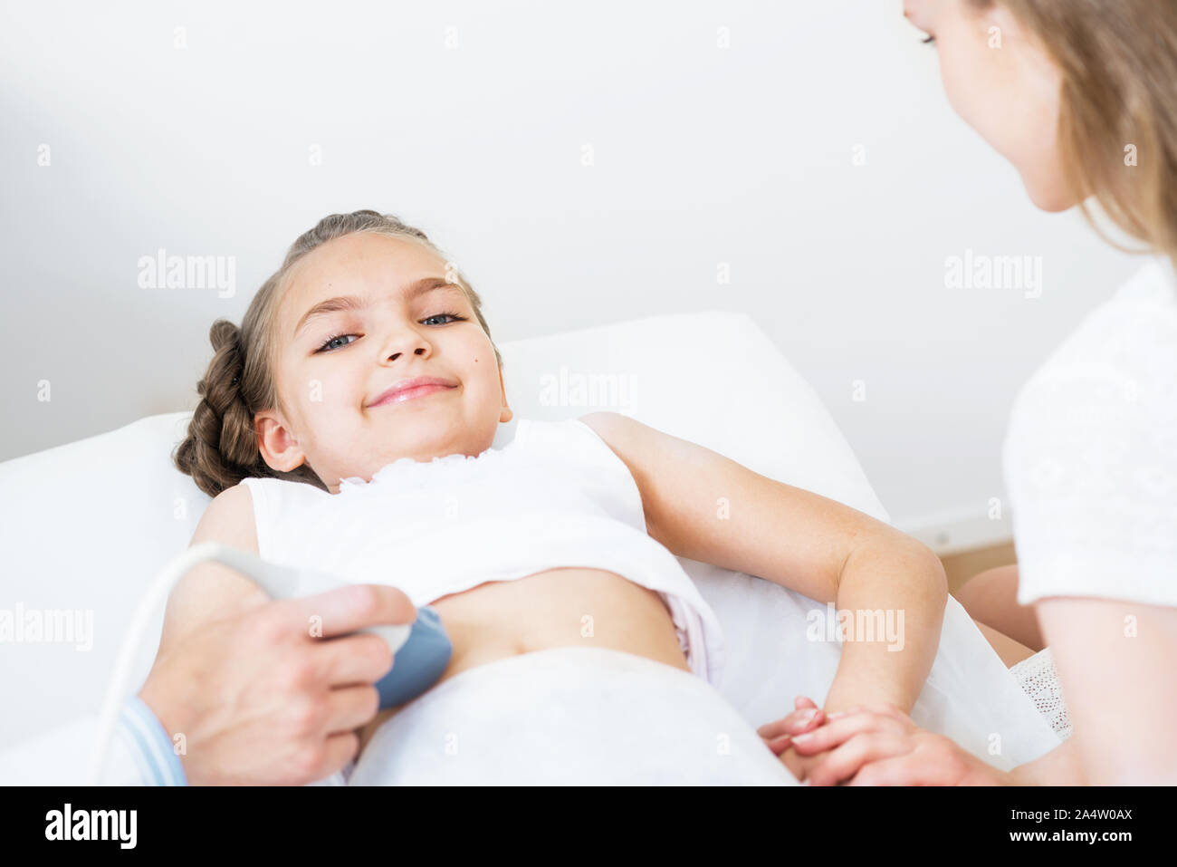 Doctor ultrasound examines little girl belly at hospital. Abdominal ...
