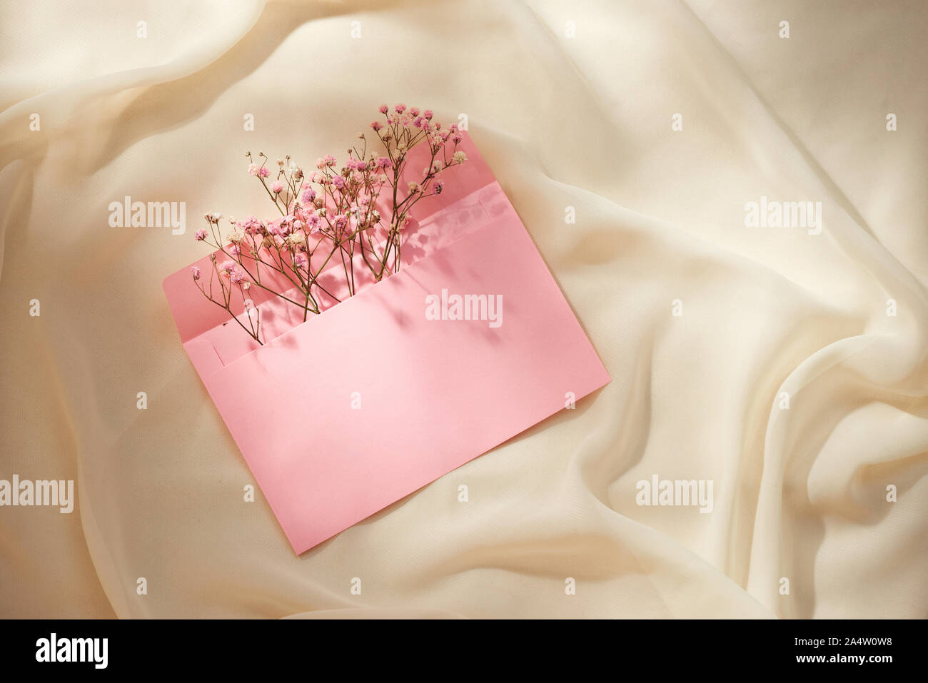 Pink envelope with a spring flower arrangement. Flat lay, top view ...