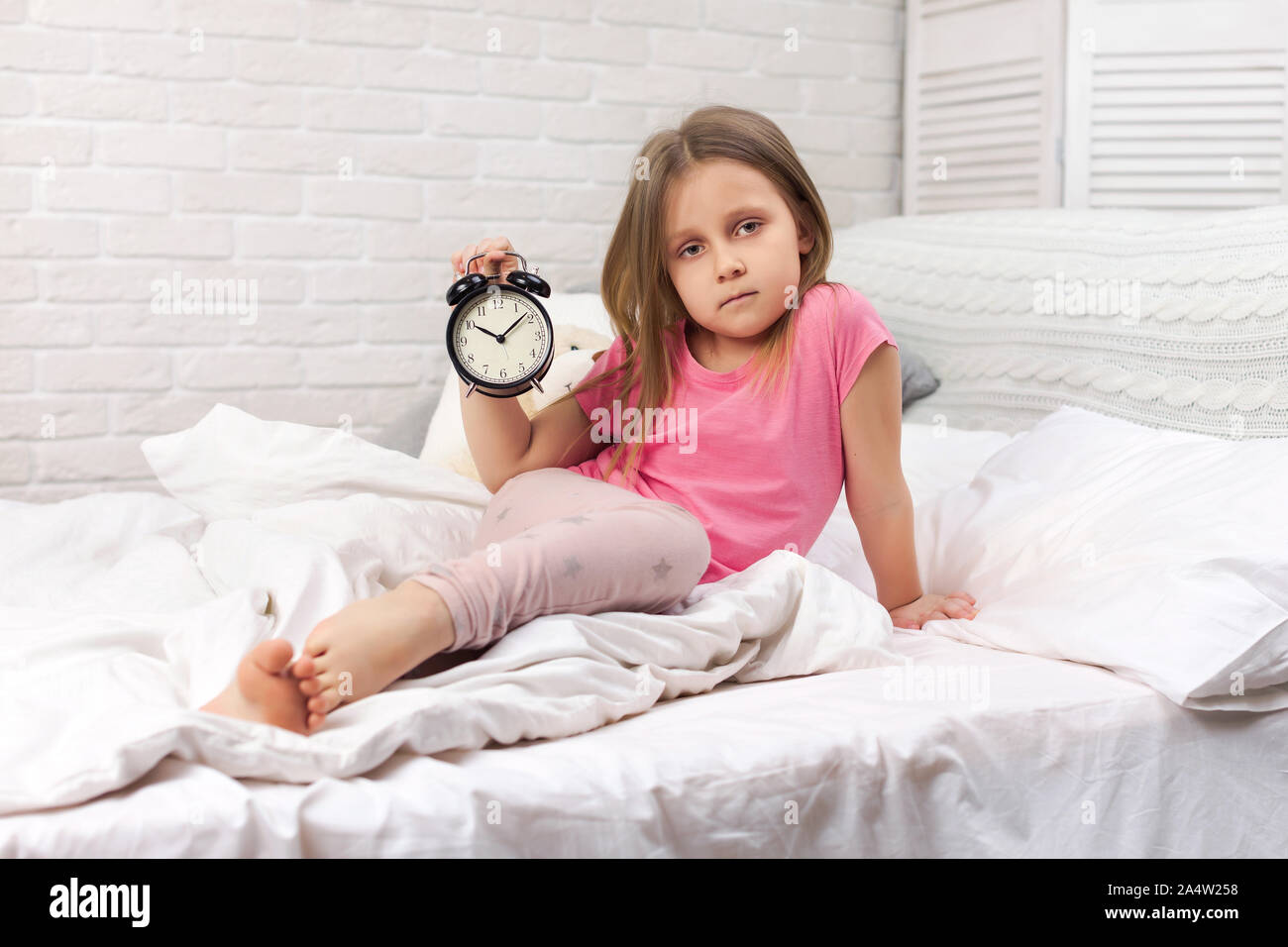 tired sleepy little child girl in pyjamas with clock in bed. good ...