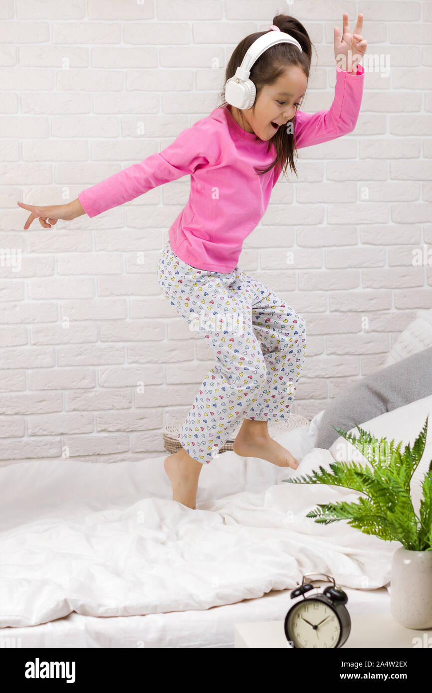 little child baby girl listening to the music with the headphones and ...
