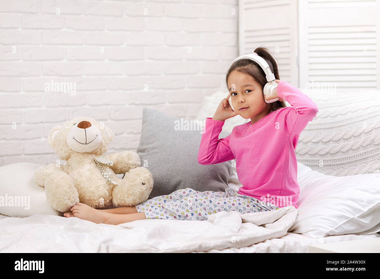 little child baby girl listening to the music with the headphones ...