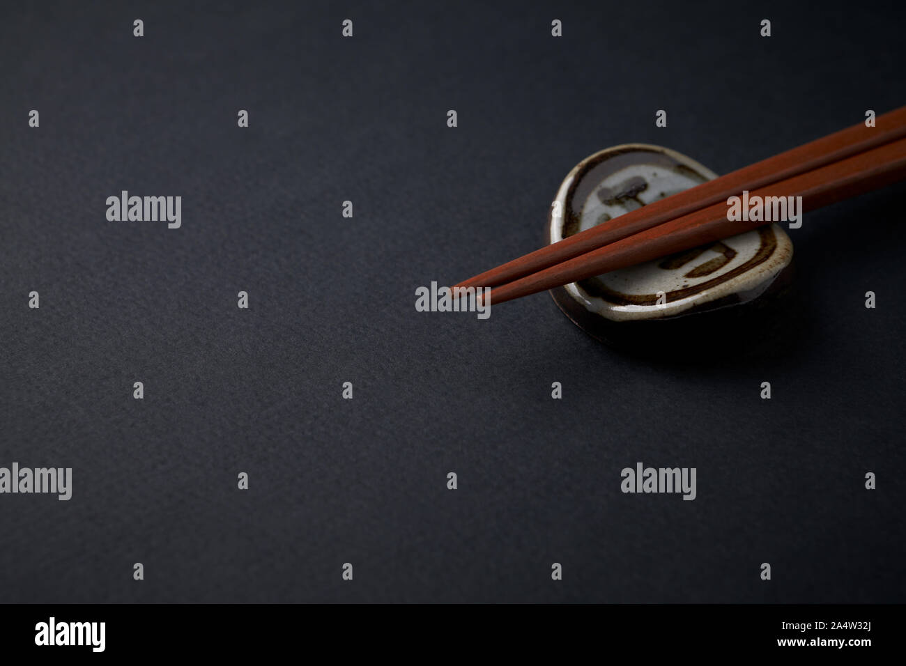 Wooden chopsticks and chopstick rest on black paper background. Close ...