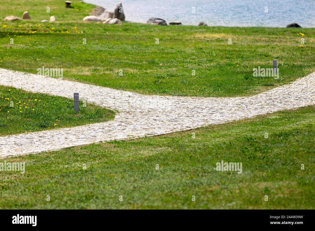 Crossroads of a stone granite path. Around the grass and in the ...