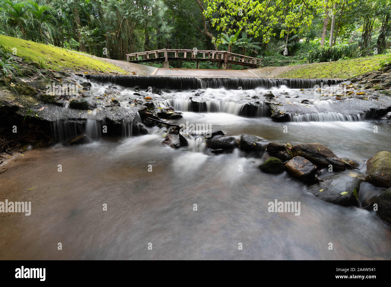 Small waterfall with old wooden bridge Stock Photo - Alamy