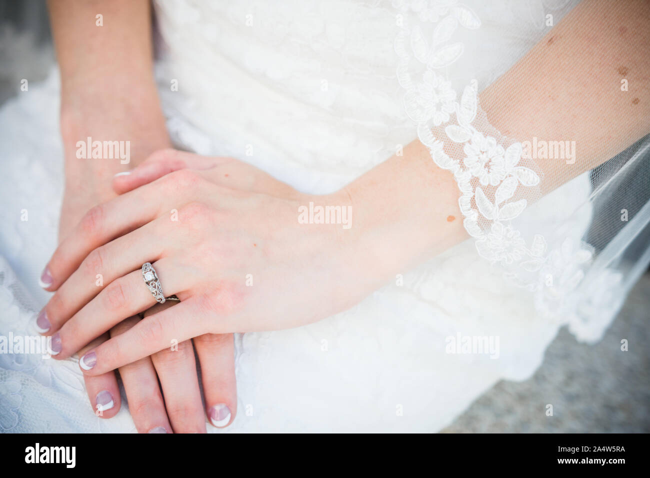 Bride shows off wedding ring and veil against elegant white dress Stock ...