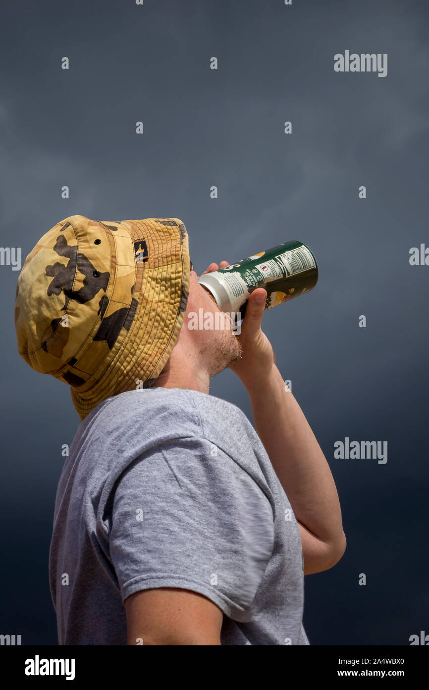 hatted man drinking alcohol with approaching storm Stock Photo - Alamy