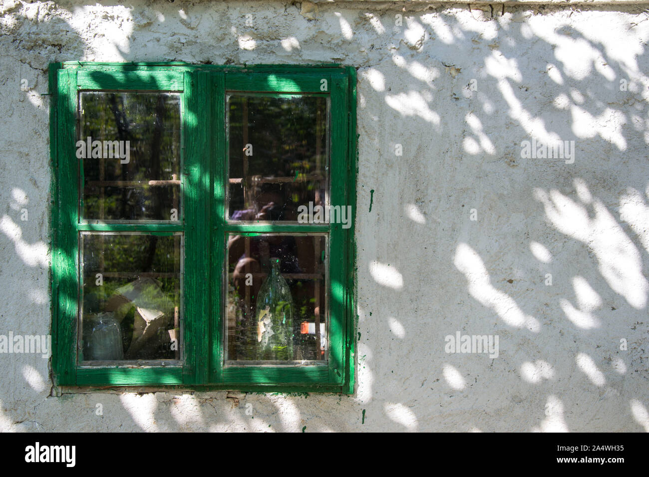 Old rusty green window with bottles behind the glass, building exterior ...