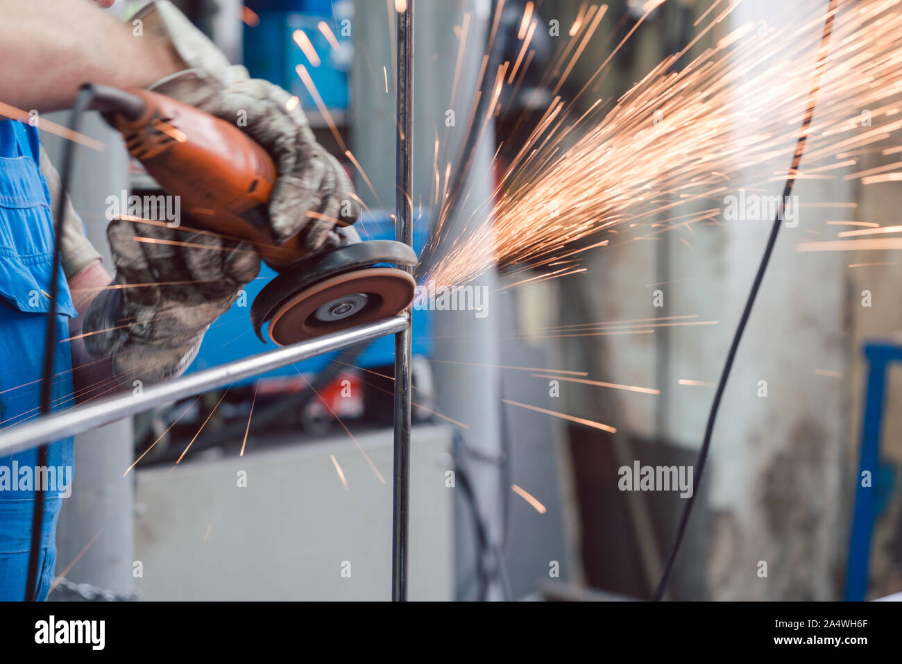 Worker in metal factory grinding workpiece with sparks flying Stock ...