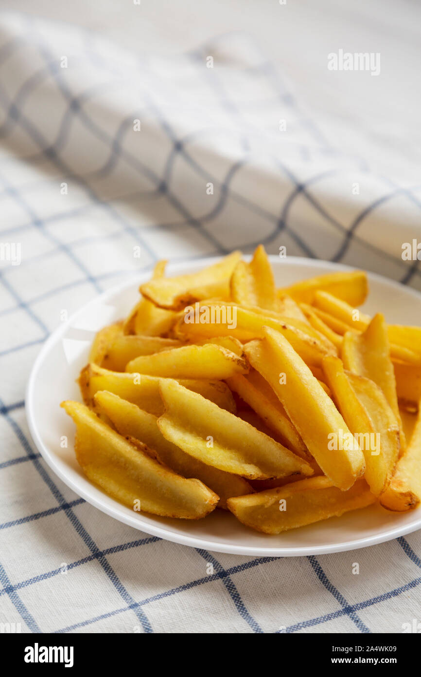 Homemade french fries with salt on a white plate, side view. Close-up ...