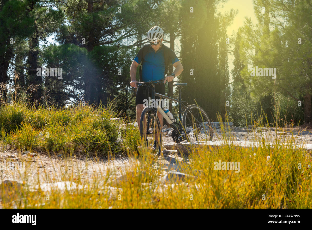 male athletic cyclist walking with his bike on a mountain path Stock ...